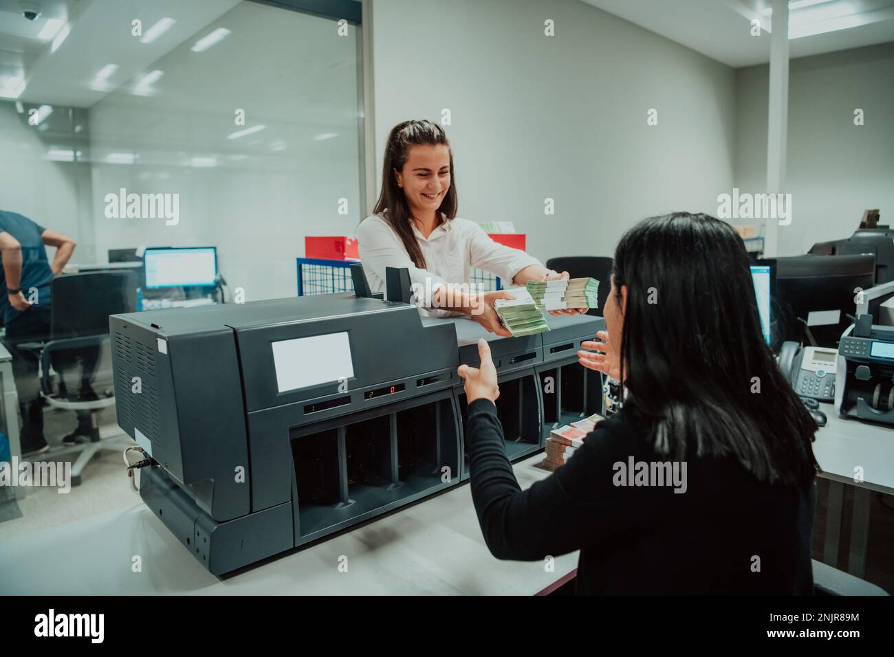 Bank employees using money counting machine while sorting and counting ...