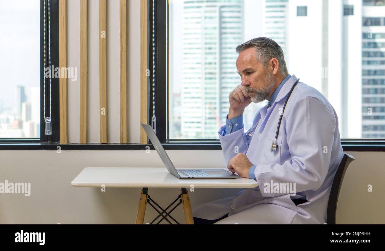 Senior professor with mustache and beard reading email on laptop ...