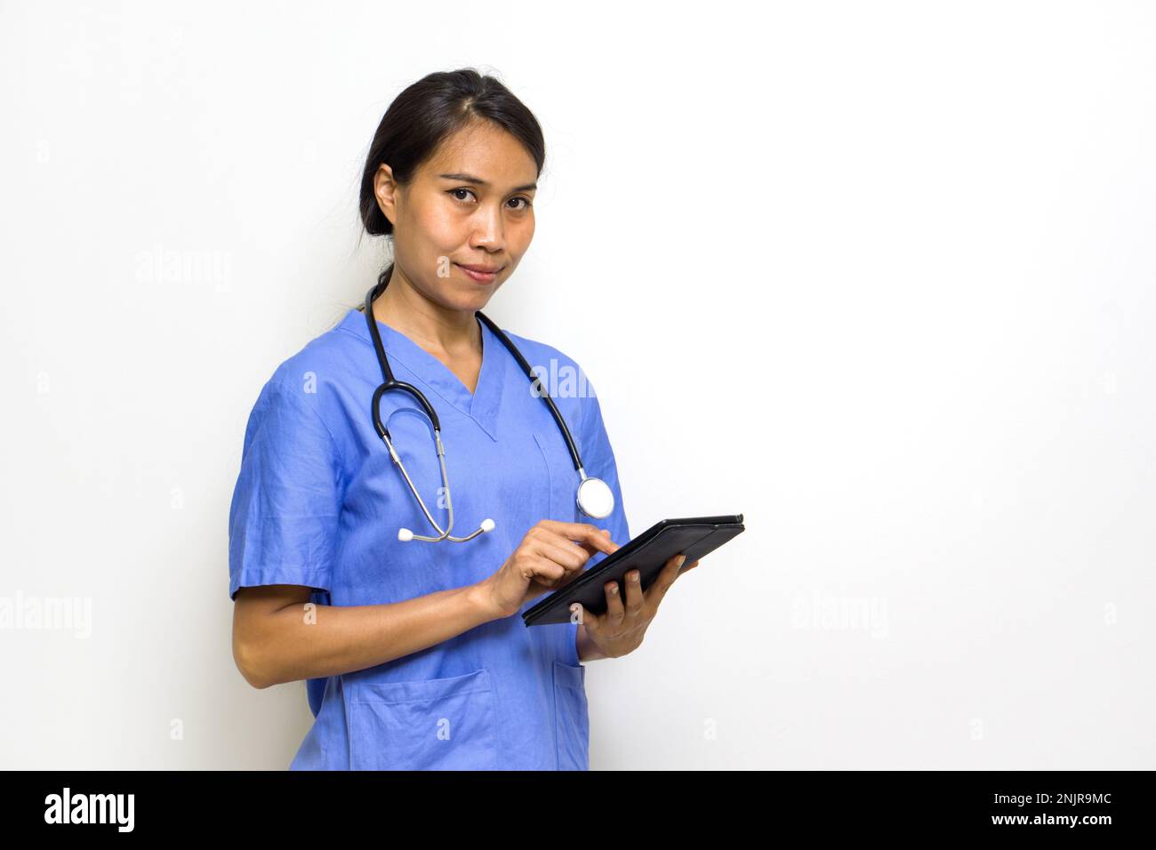Woman physical therapist in blue uniform and stethoscope typing on ...