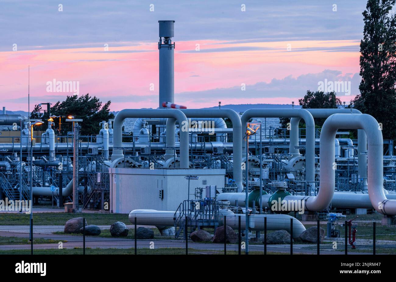 The sun rises behind the pipe systems and shut-off devices at the gas ...
