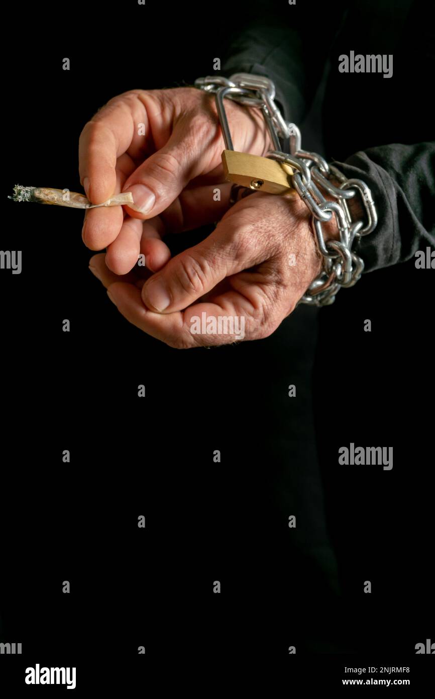 man smoking with chained hands on black background, concept of ...