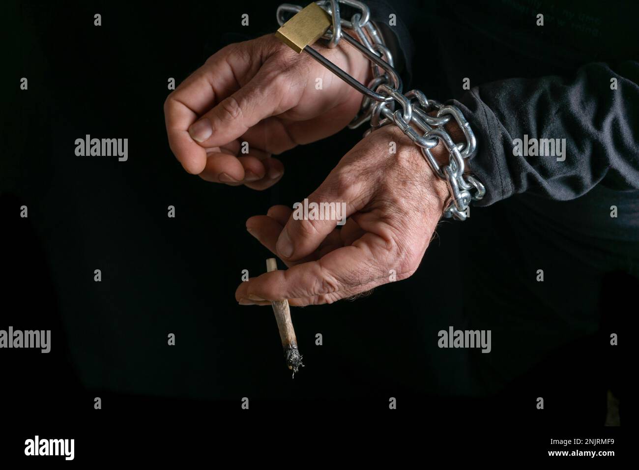 man smoking with chained hands on black background, concept of ...