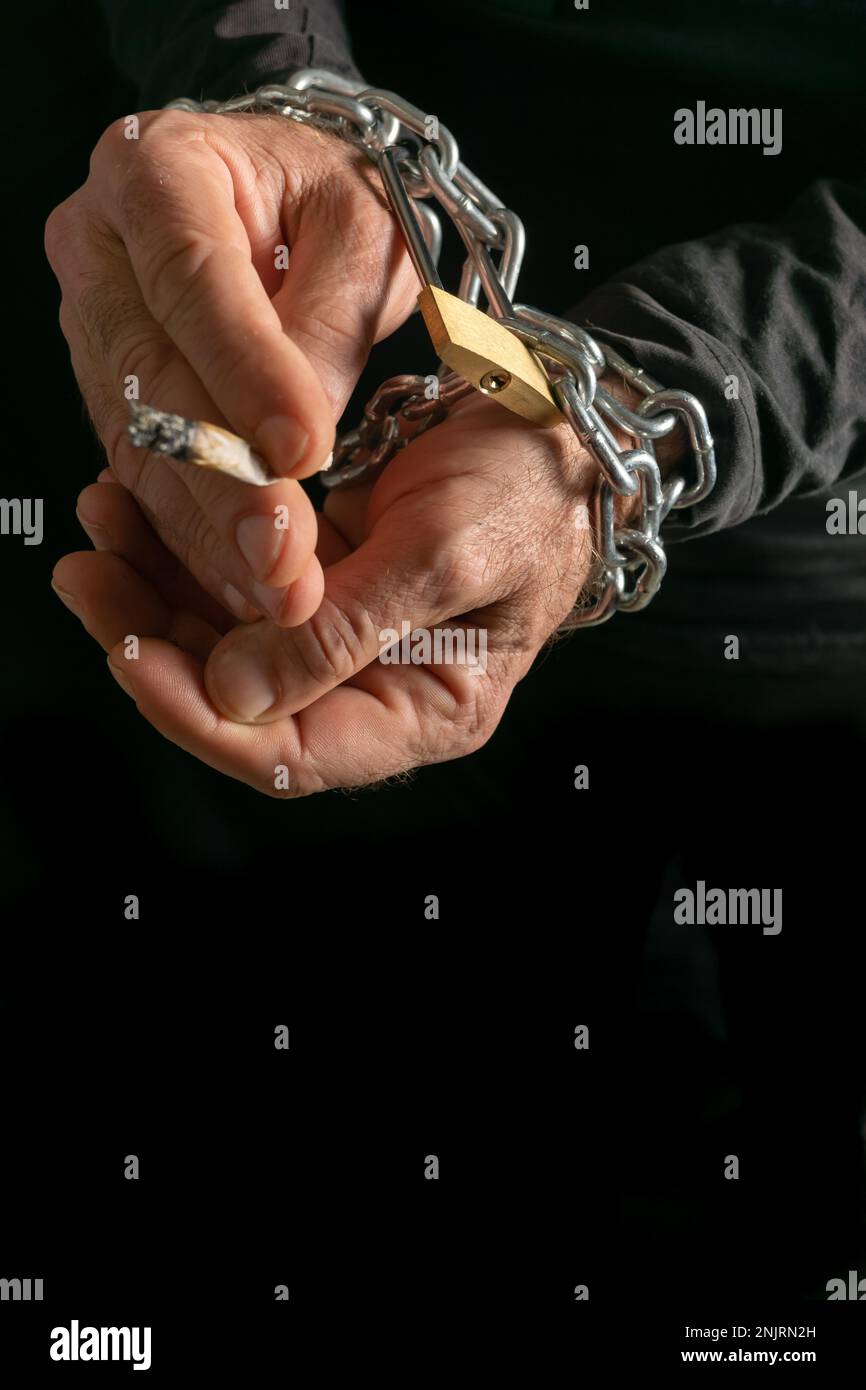 man smoking with chained hands on black background, concept of ...