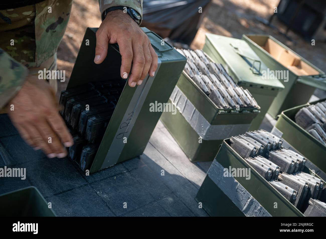 A U.S. Air Force Airman loads empty magazines into ammunition cans ...