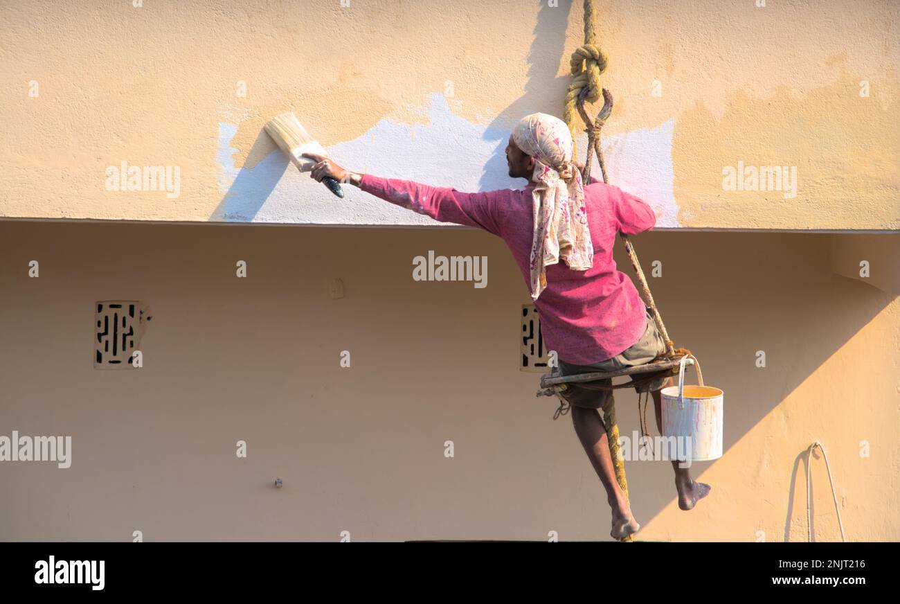 Unidentified Paint worker hanging on rope based tool to paint exterior ...