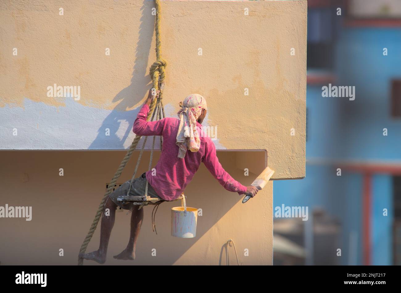 Unidentified Paint worker hanging on rope based tool to paint exterior ...