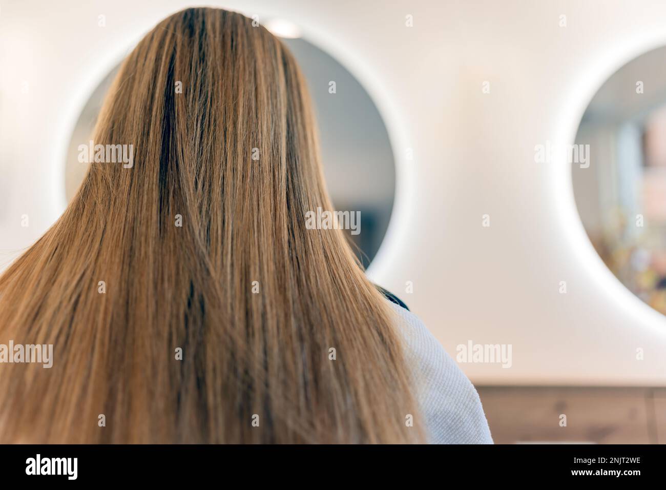 Low angle back view of anonymous female client sitting near round ...