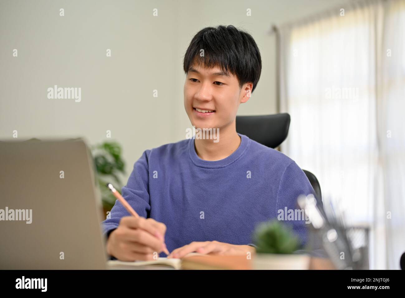 Smart and happy young Asian male college student doing homework or ...