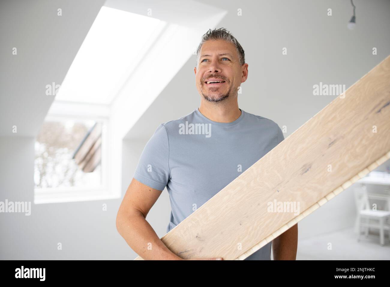 Middle aged man with grey hair and grey shirt laying parquet floor in ...
