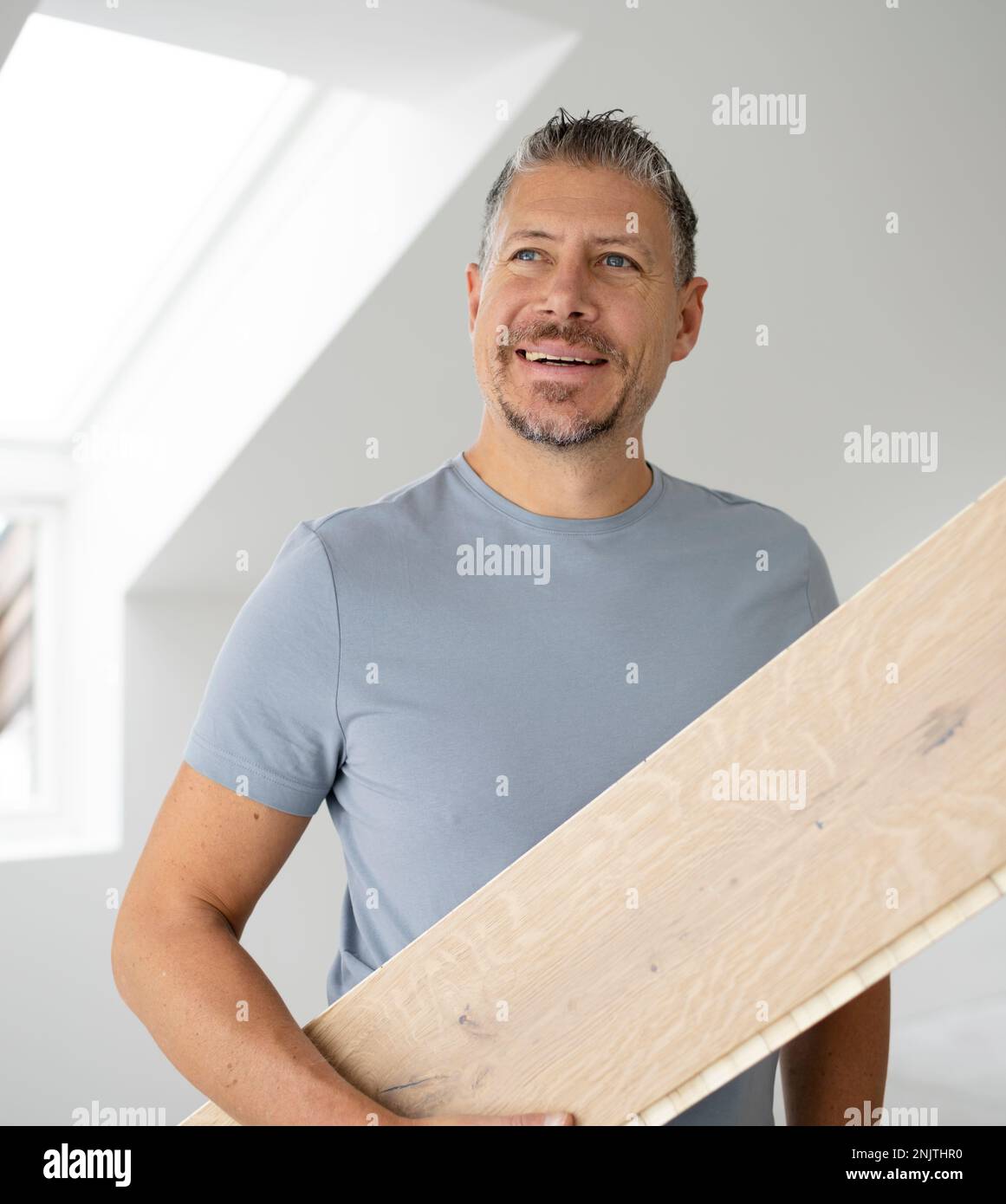 Middle aged man with grey hair and grey shirt laying parquet floor in ...