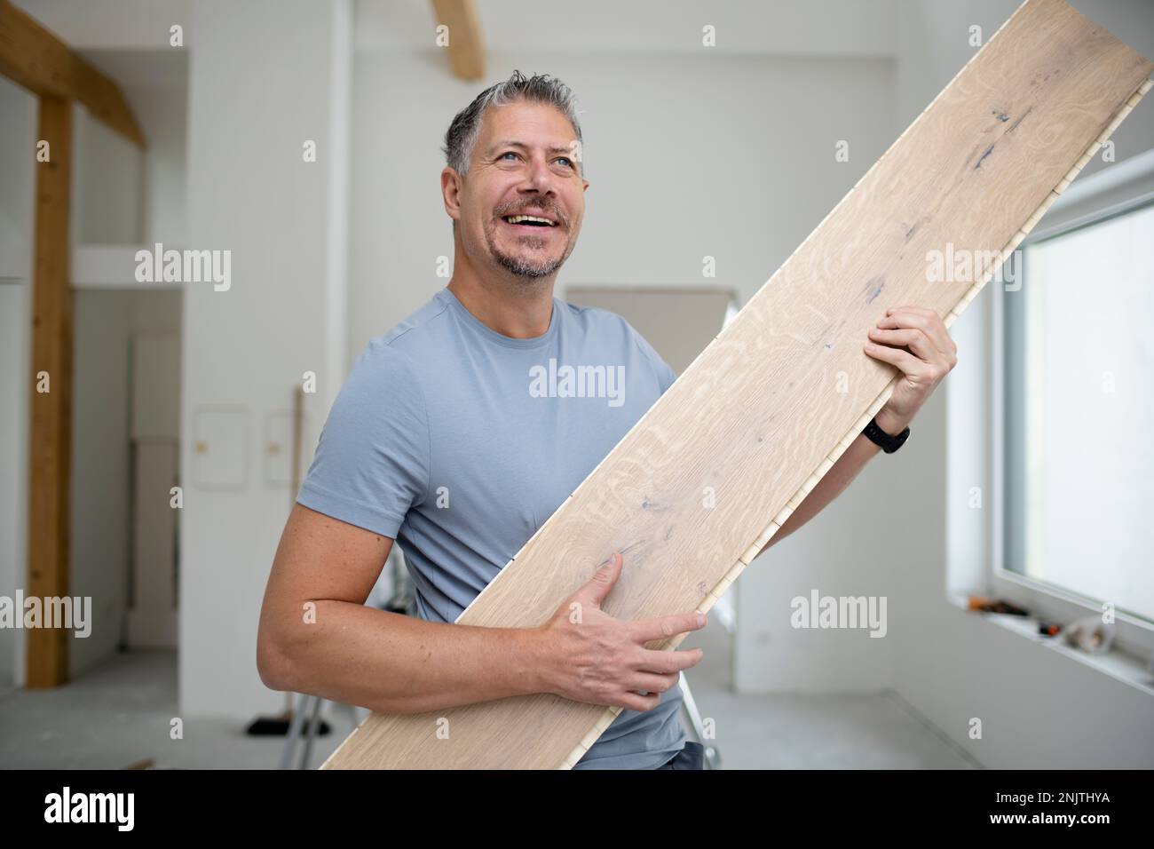 Middle aged man with grey hair and grey shirt laying parquet floor in ...