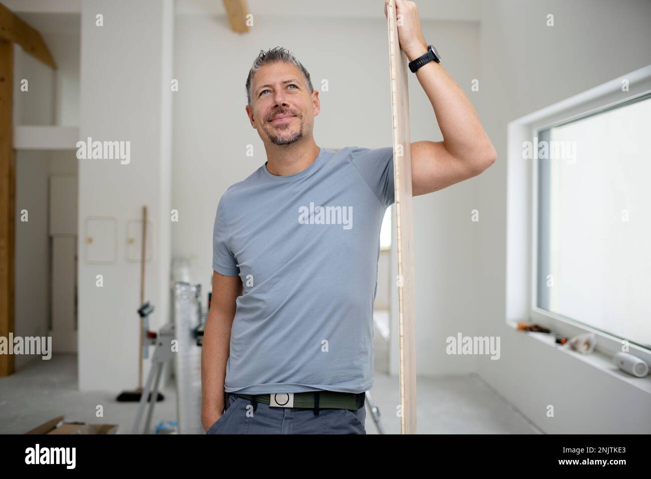 Middle aged man with grey hair and grey shirt laying parquet floor in ...
