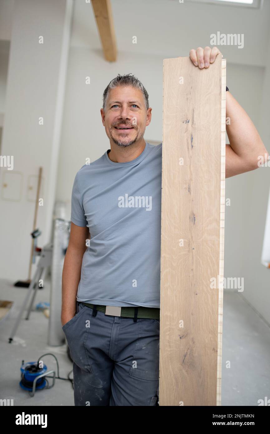 Middle aged man with grey hair and grey shirt laying parquet floor in ...