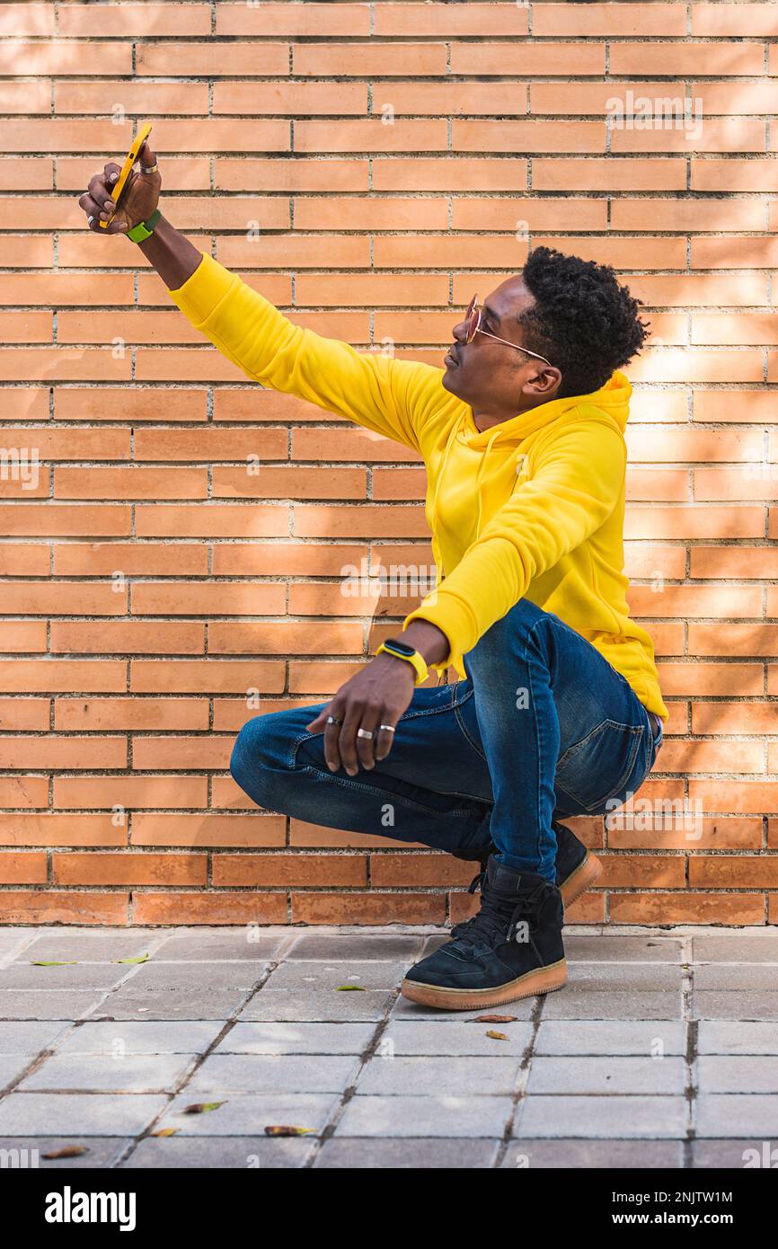 Full body side view of African man in yellow hoodie and sunglasses ...