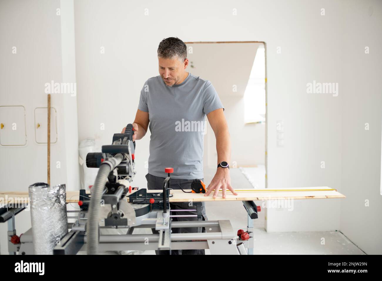 Middle aged man with grey hair and grey shirt laying parquet floor in ...