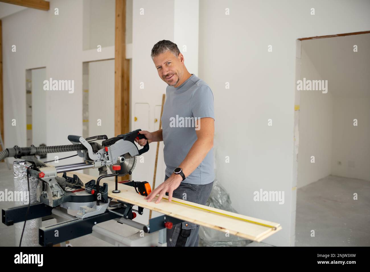 Middle aged man with grey hair and grey shirt laying parquet floor in ...