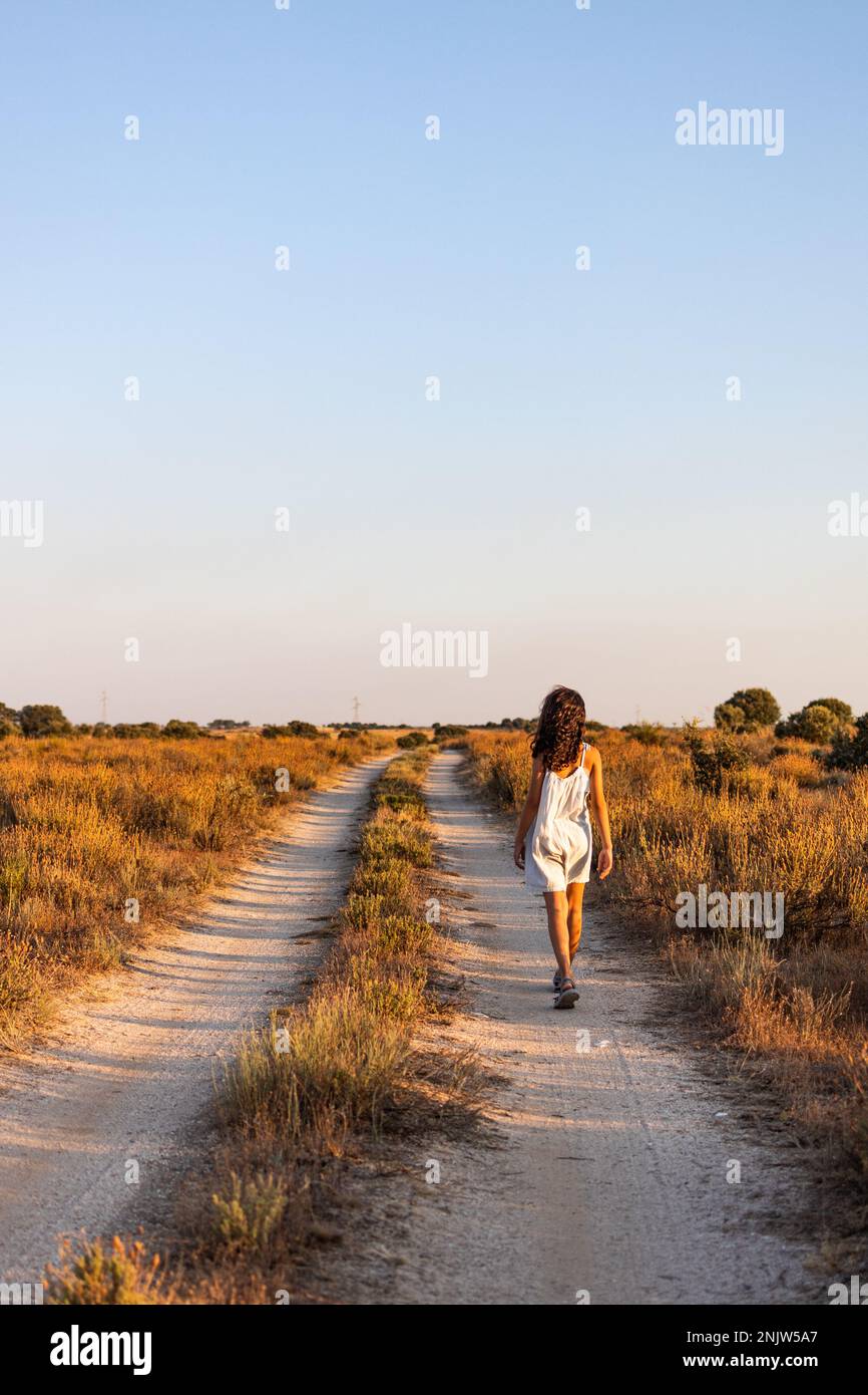 Lonely girl walking on a country road. Back view Stock Photo - Alamy