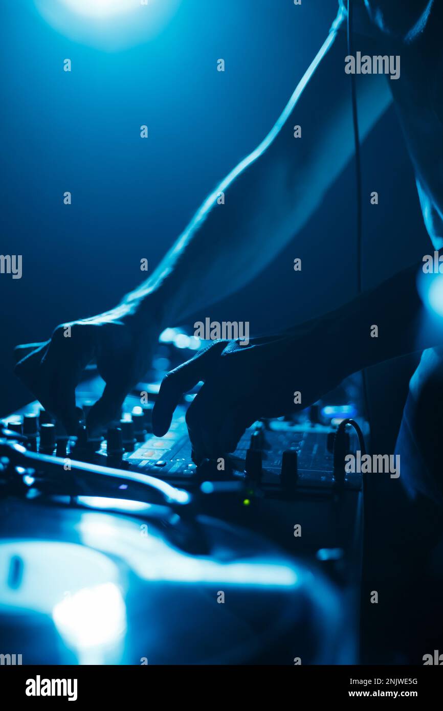 Club dj mixing music set on party in bright blue lights. Silhouette of ...