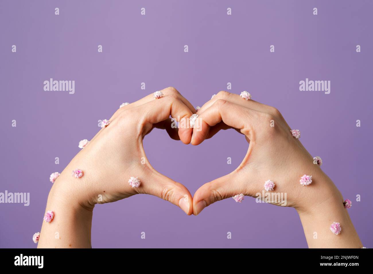 Heart hand gesture on purple. Small flowers on skin, spring vibe Stock ...