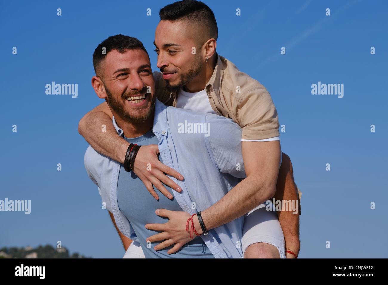 Man carrying his boyfriend on his back while having fun together ...