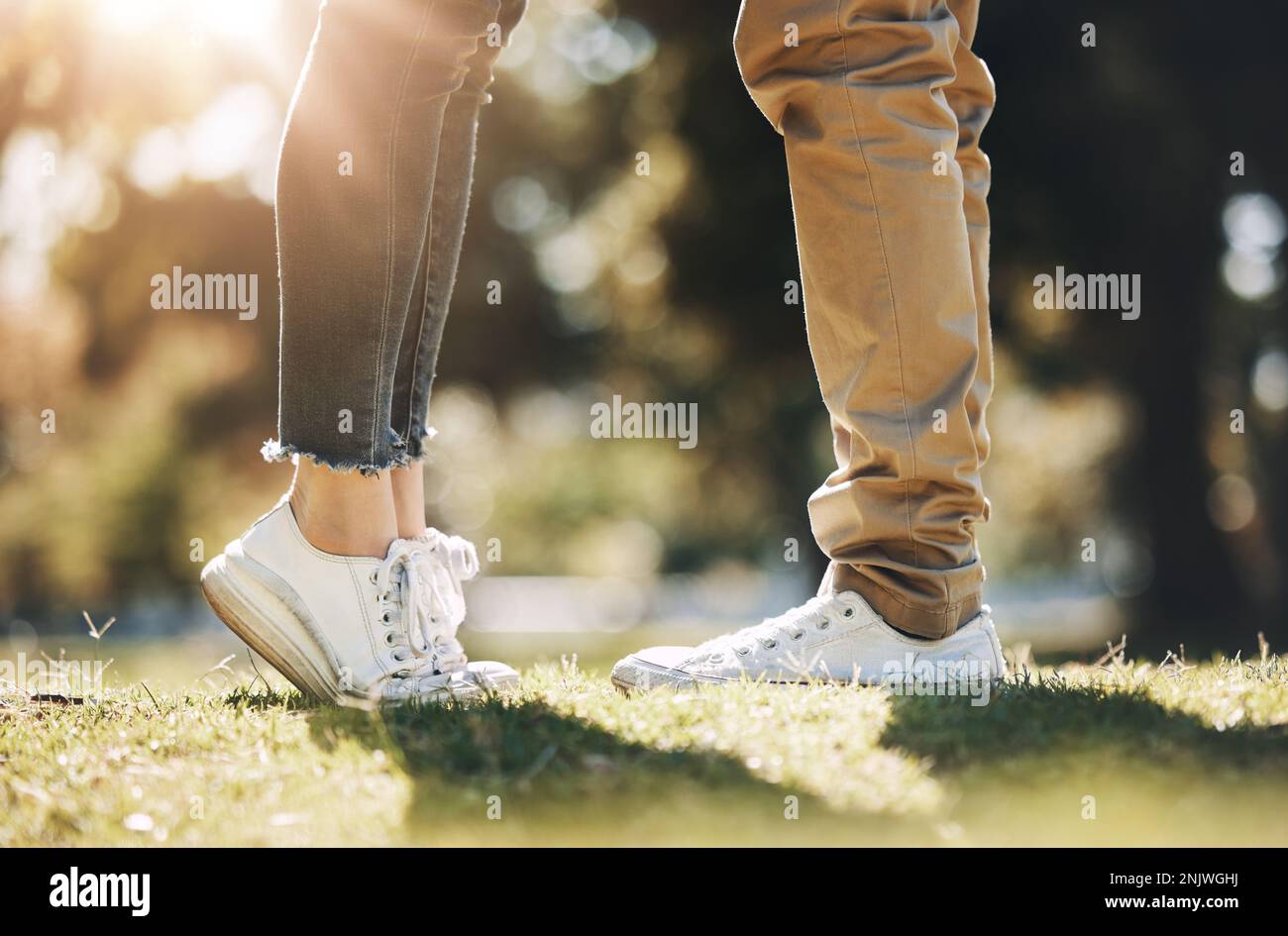 Couple, legs and feet standing on grass field for love, affection or ...