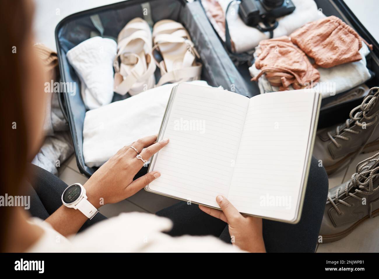 Travel, suitcase and notebook with hands of woman for planning ...