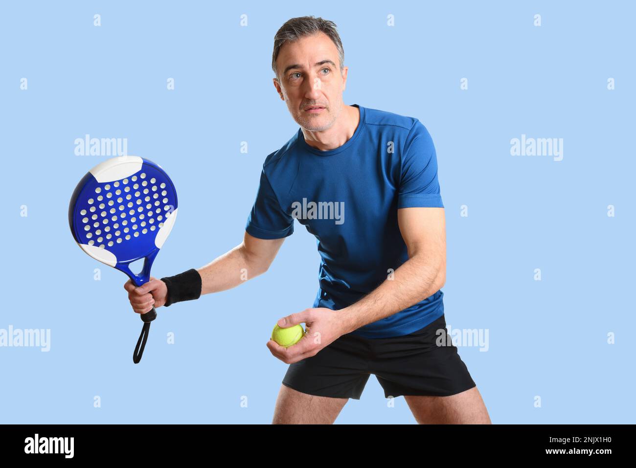 Portrait of man playing padel in position to serve with racket and ball ...