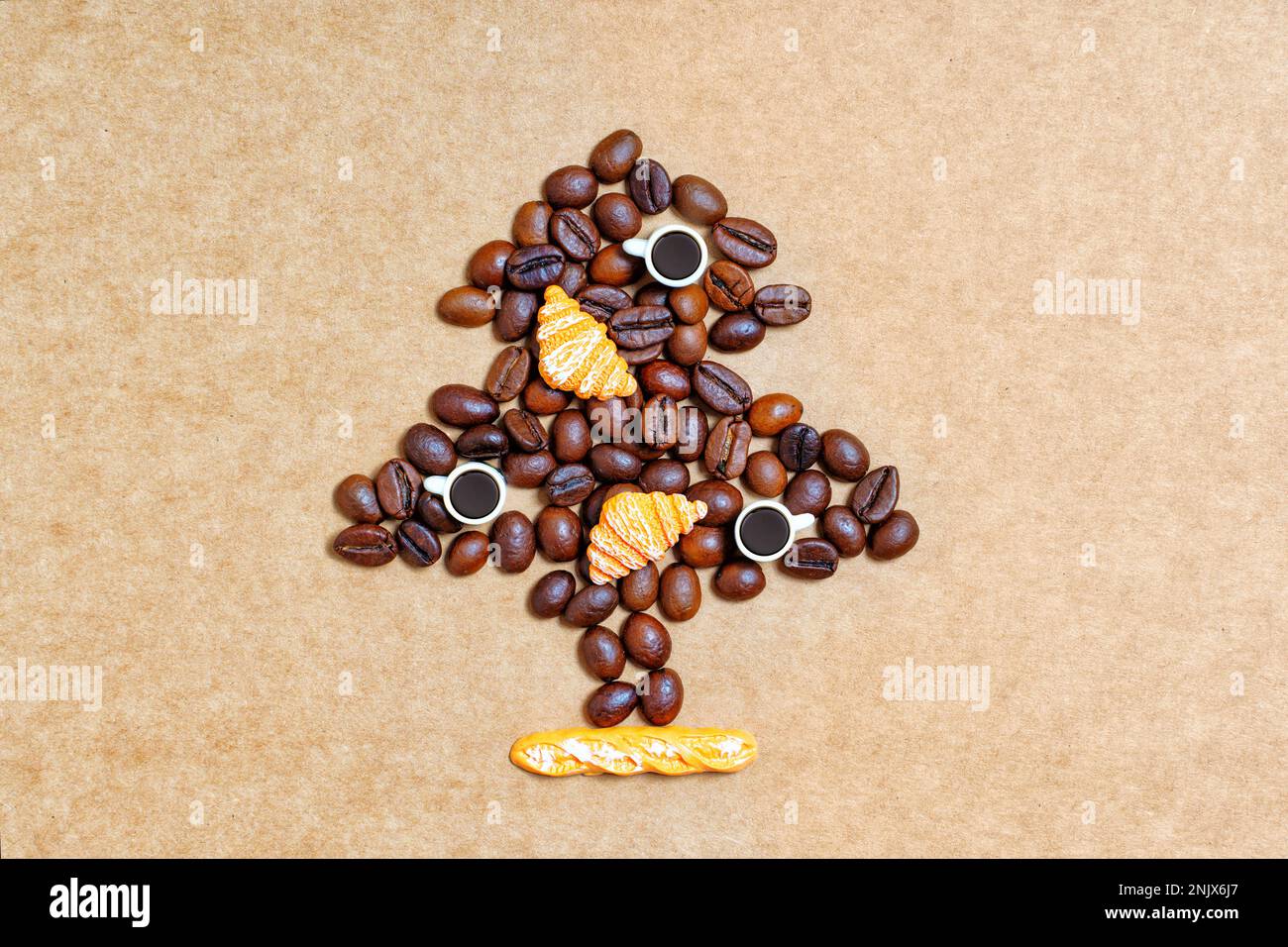 Roasted coffee beans, tiny coffee cups and toy croissants arranged into ...