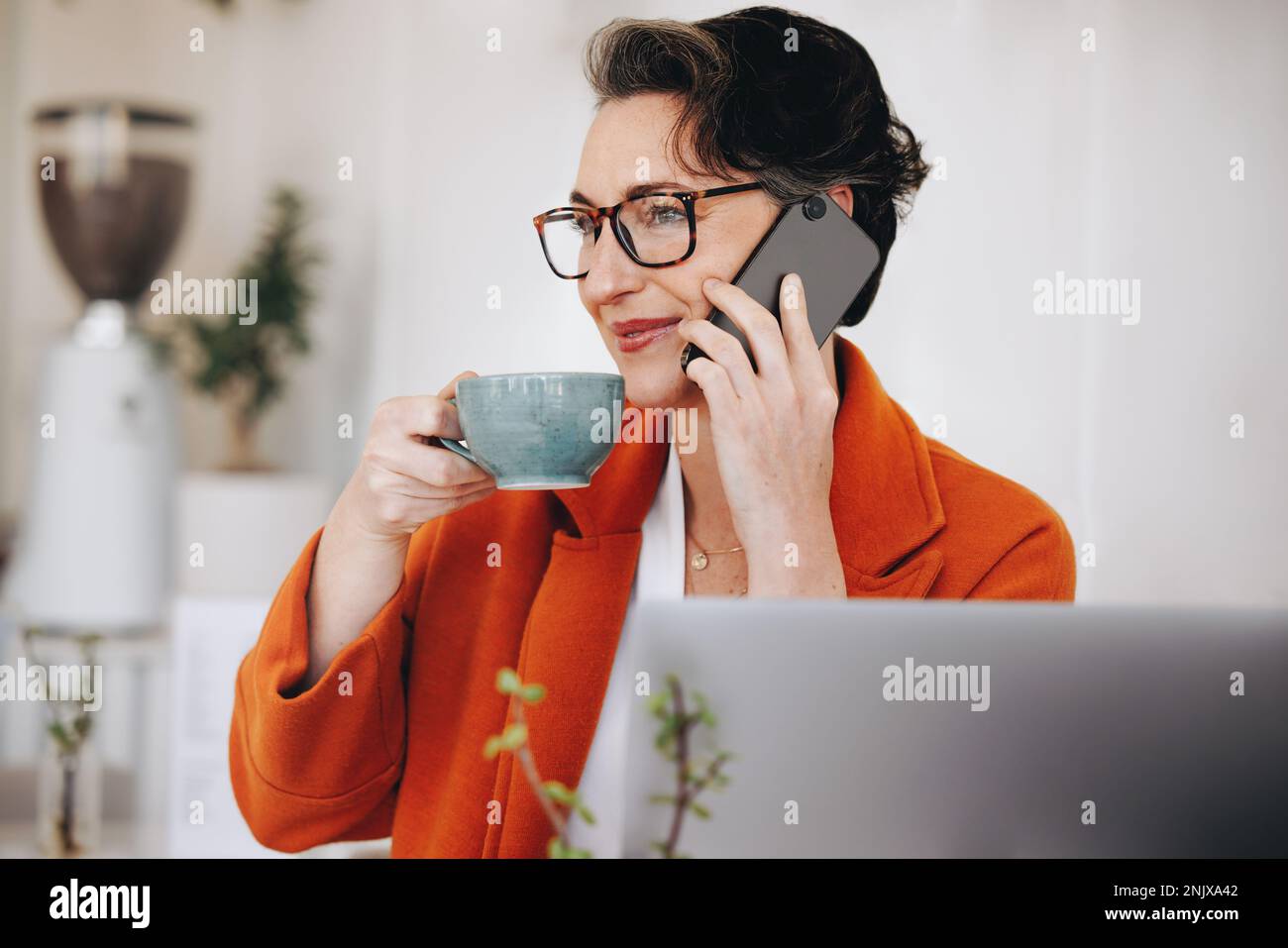 business woman drinking coffee while taking a phone call in a cafe ...