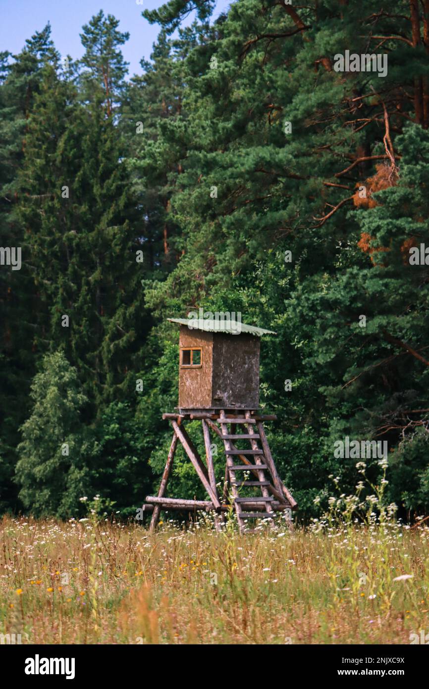 A wide shot of a hunting cabin near a forest and field intersection ...