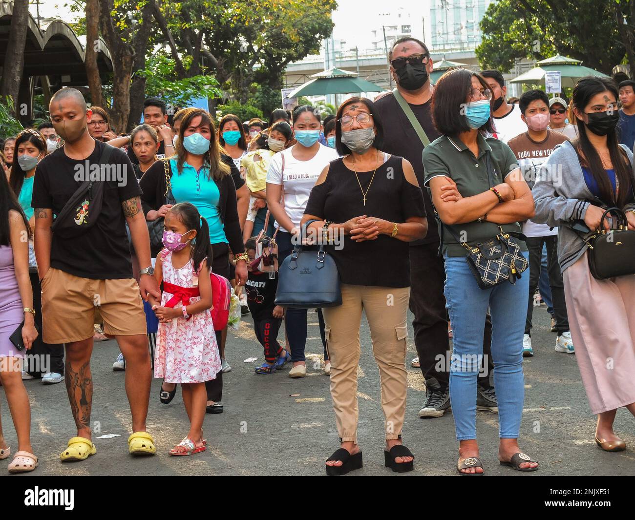 Catholic devotees with ash markings on their forehead wait to enter the ...