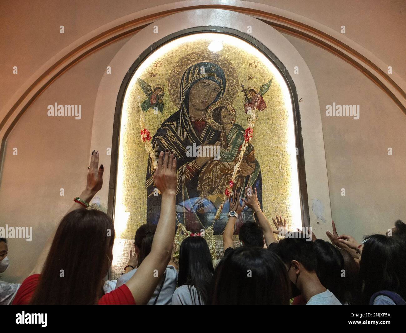 Catholic devotees raise their hands to touch the large image of mother ...
