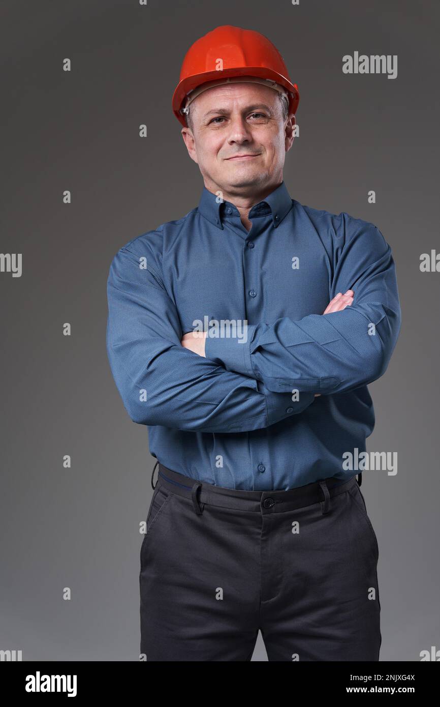 Happy mature engineer in hardhat smiling with arms crossed isolated on ...