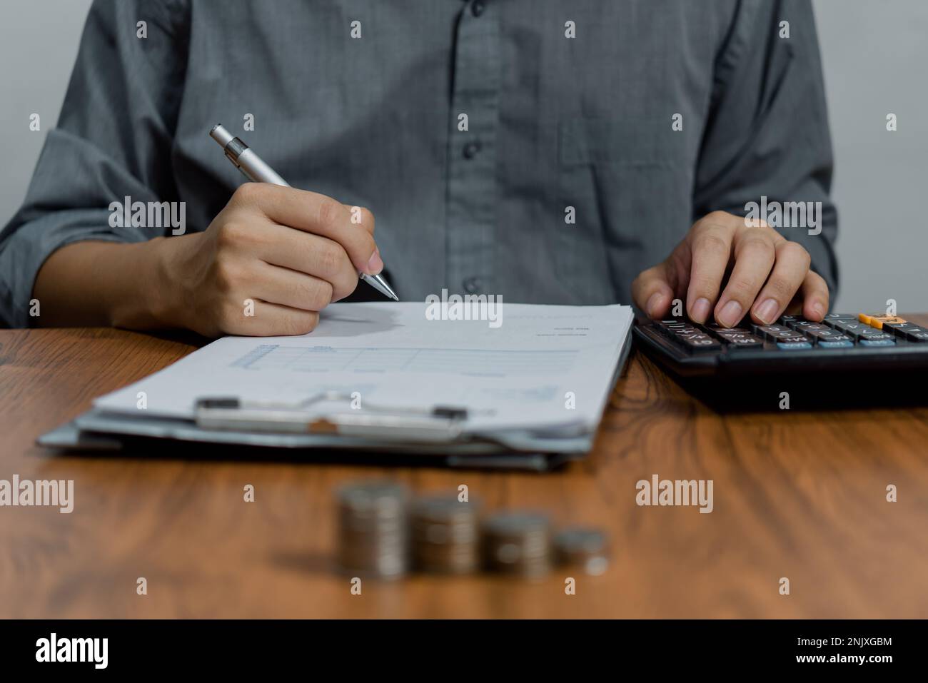 Man signing financial documents and banking and investment calculator ...