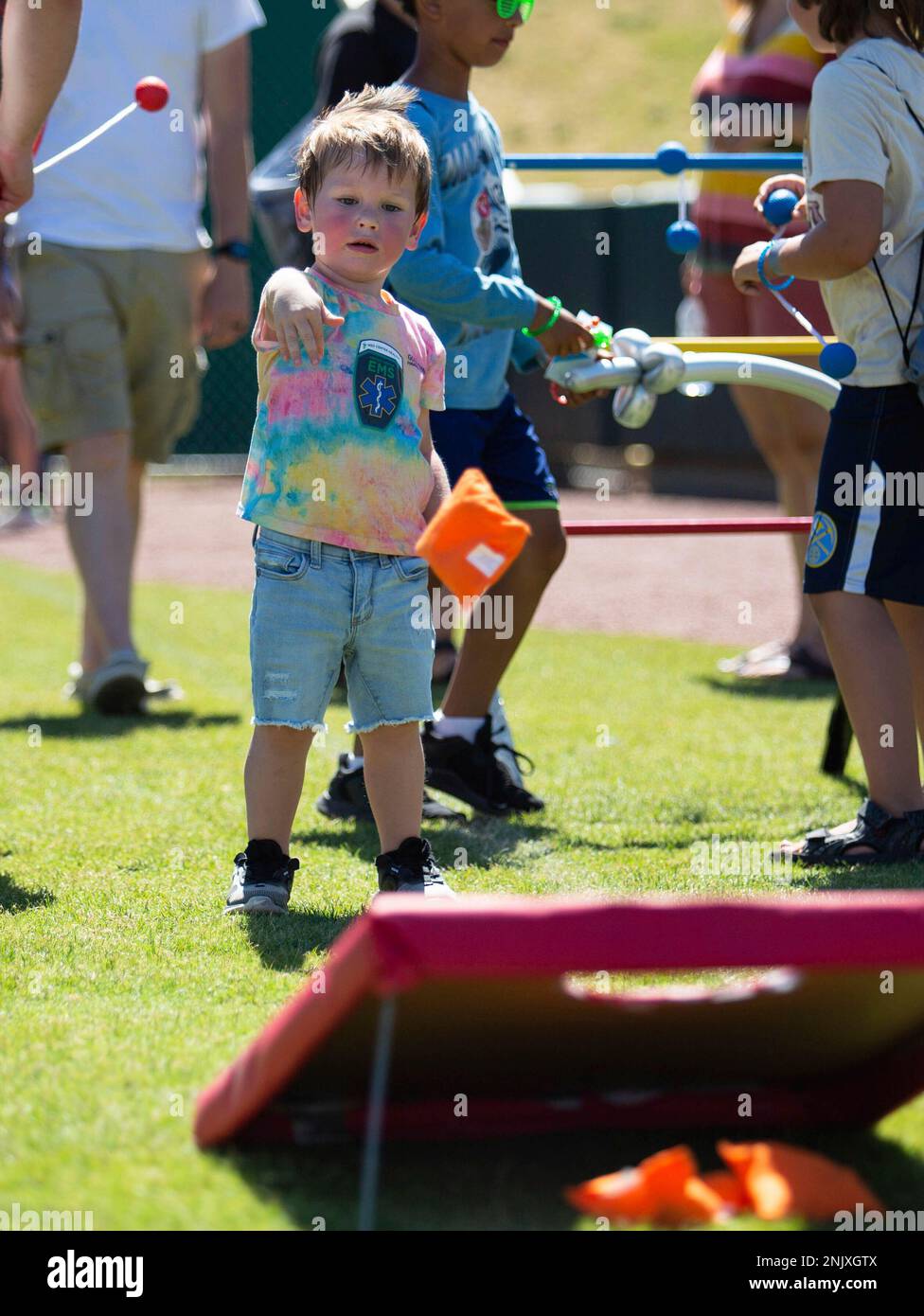 Carson Jeffries, 2, throws a bean bag at a corn hole board while ...