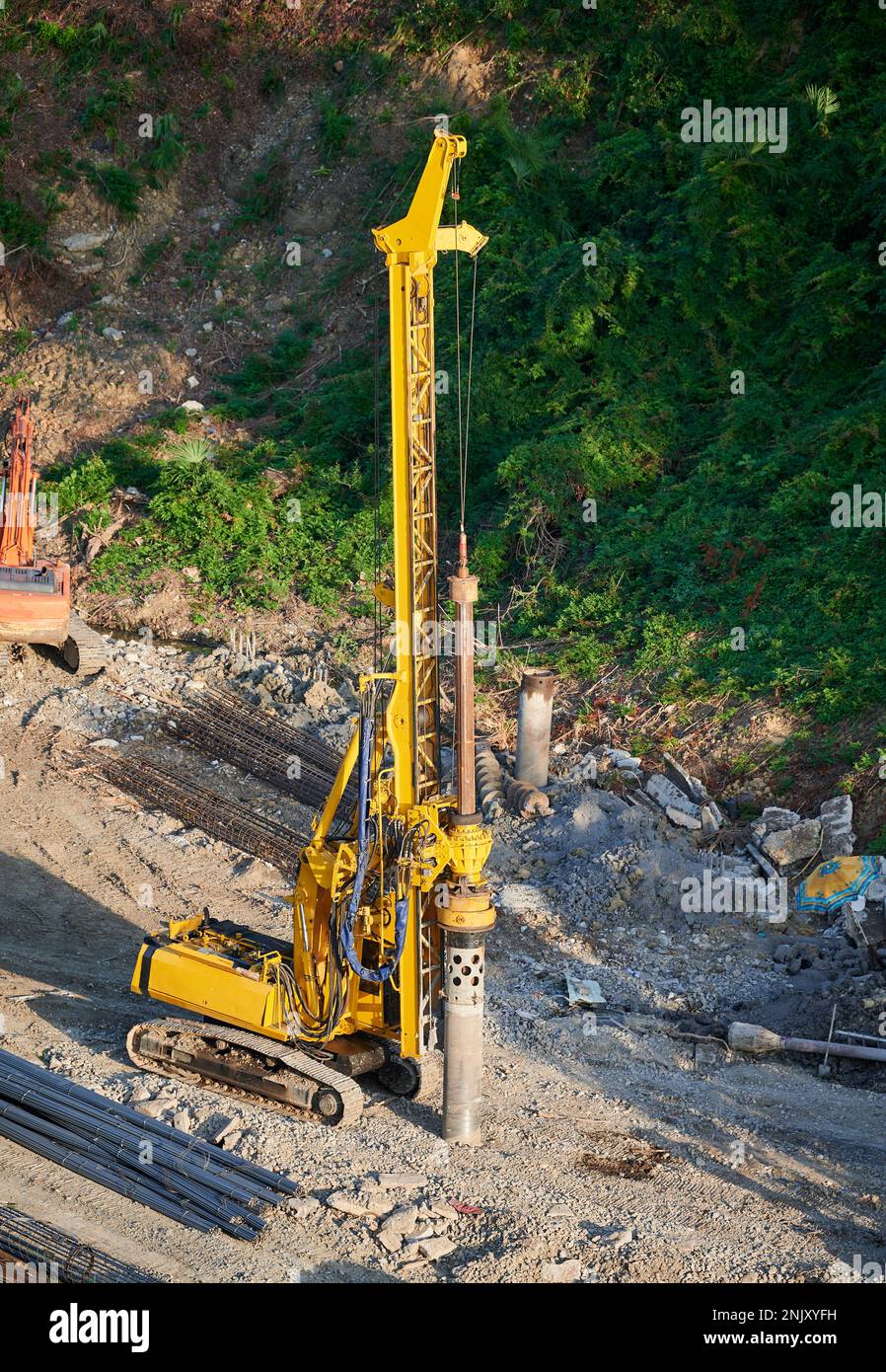 The yellow pile driver drives the foundation piles at the construction ...