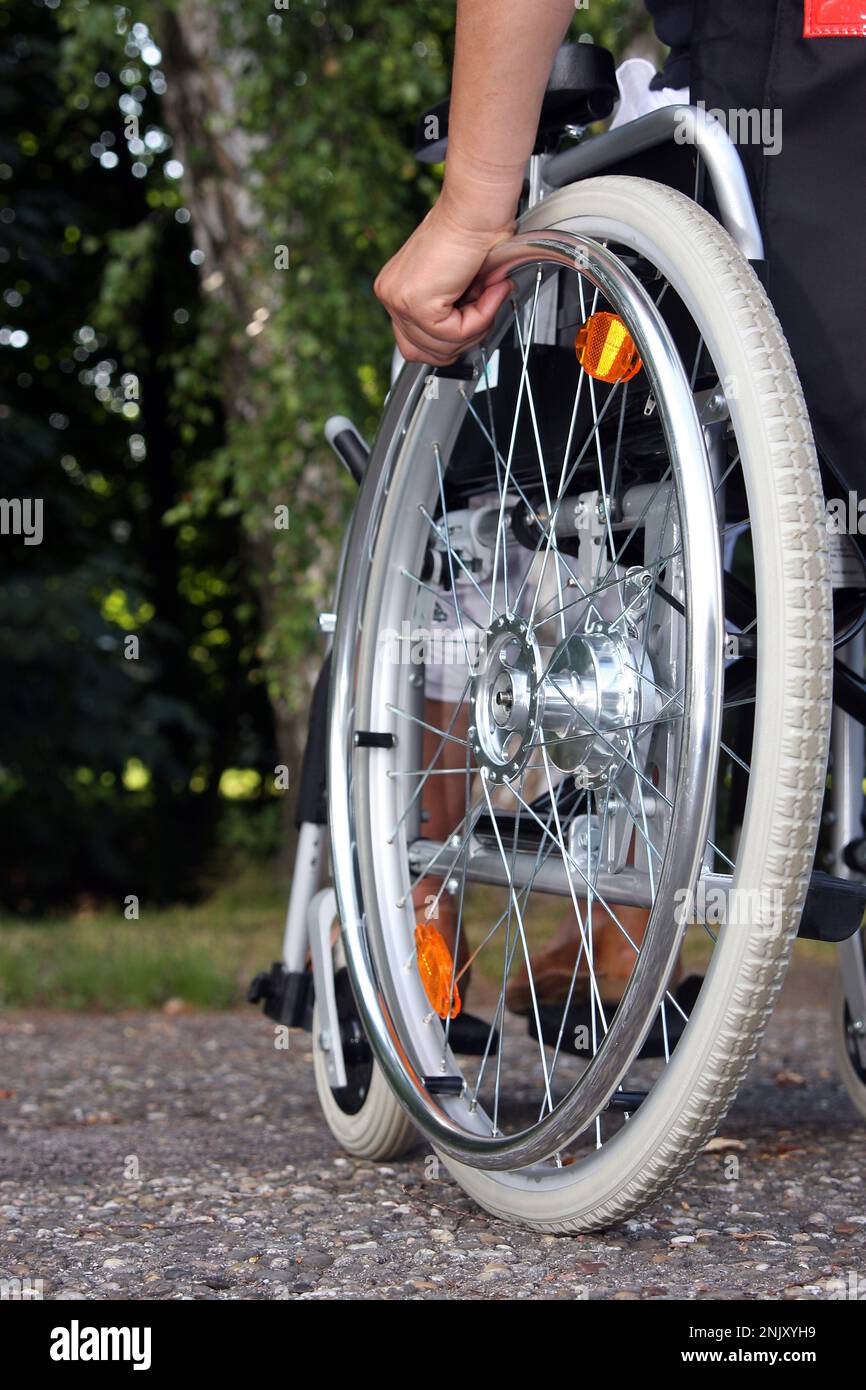 woman in a wheelchair on a path, detail Stock Photo - Alamy