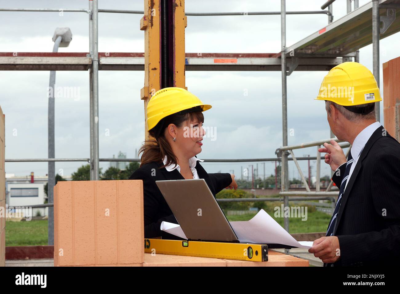 two architects with laptop, construction plan and water-level at the ...