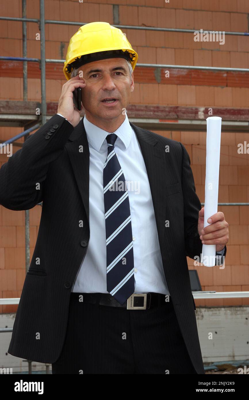 architect talking on the phone on the construction site, front view ...