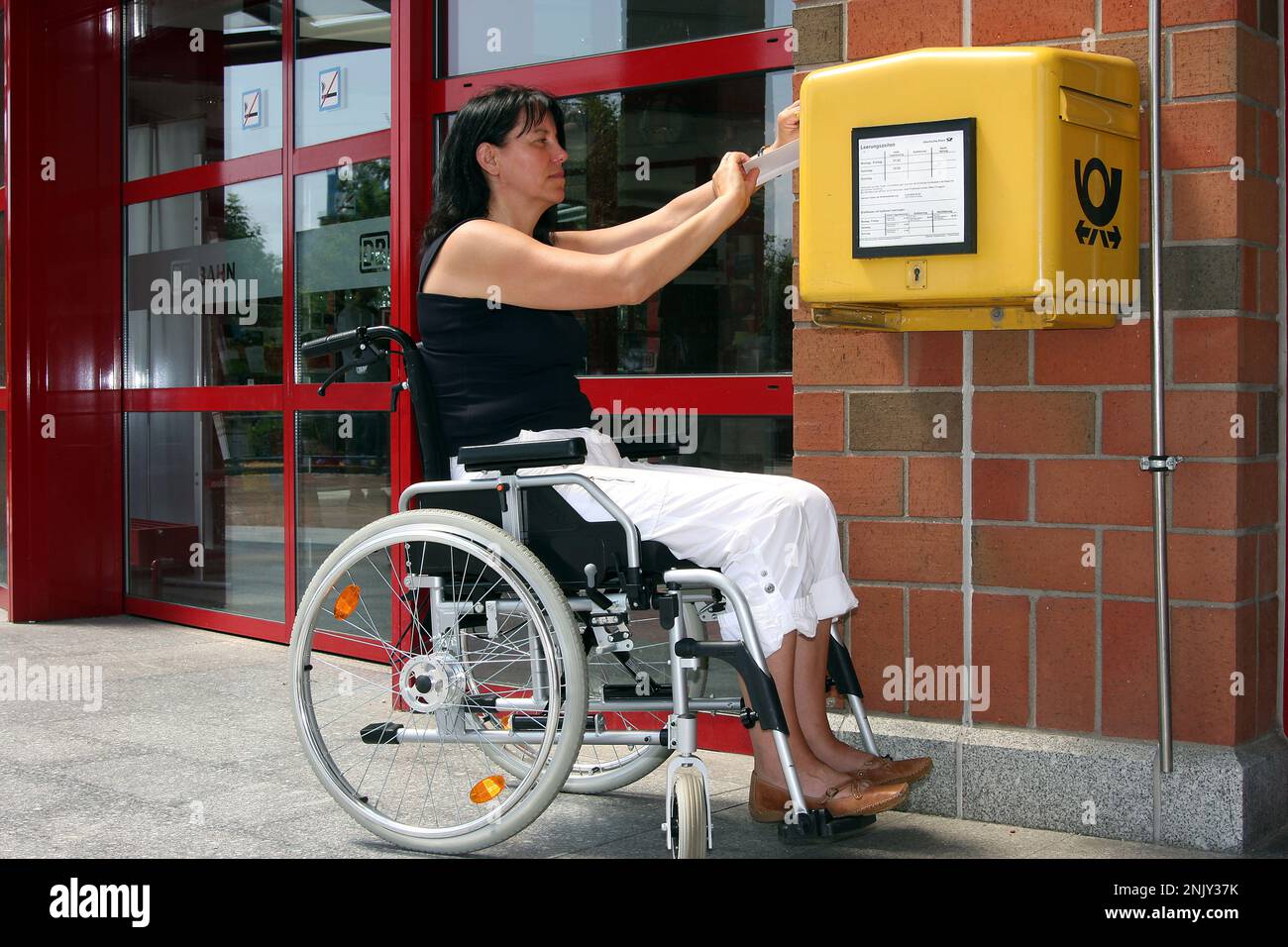 woman in wheelchair throwing mail into a letterbox Stock Photo - Alamy
