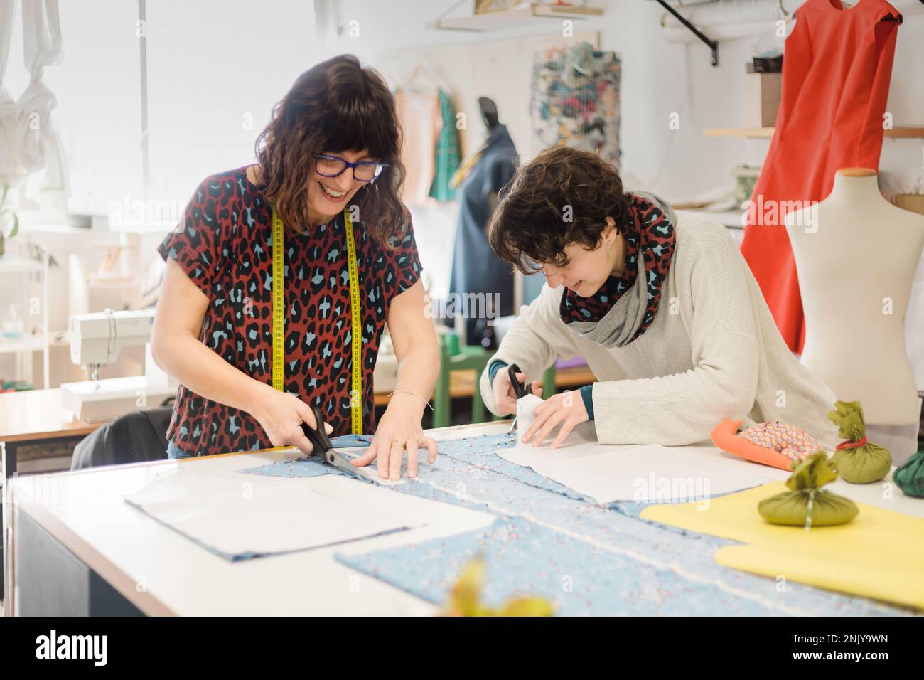 Concentrated female designers in casual outfits smiling and cutting ...