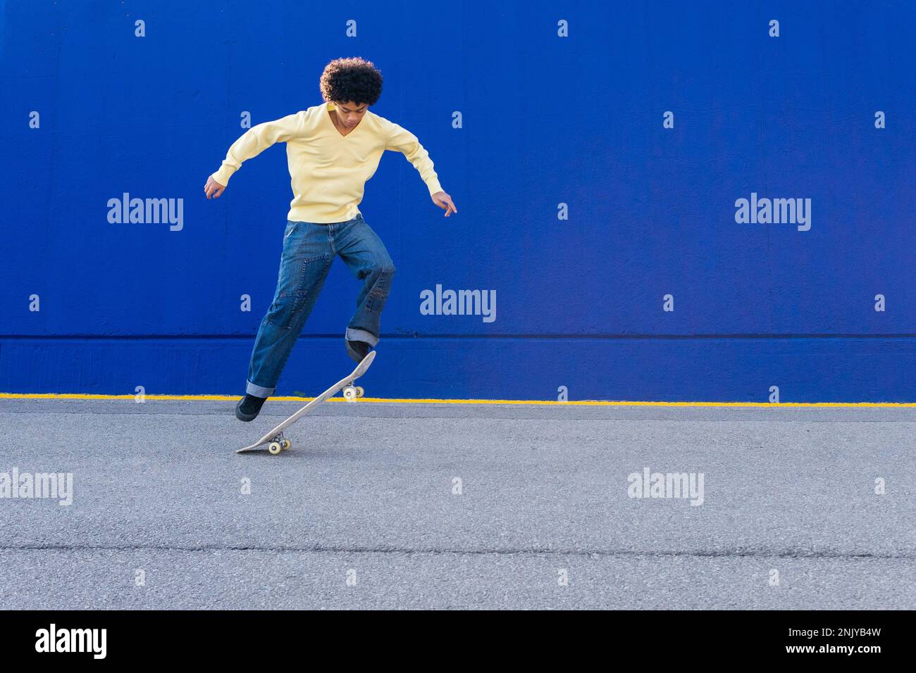 Full body of determined young male skater in casual clothes jumping on ...