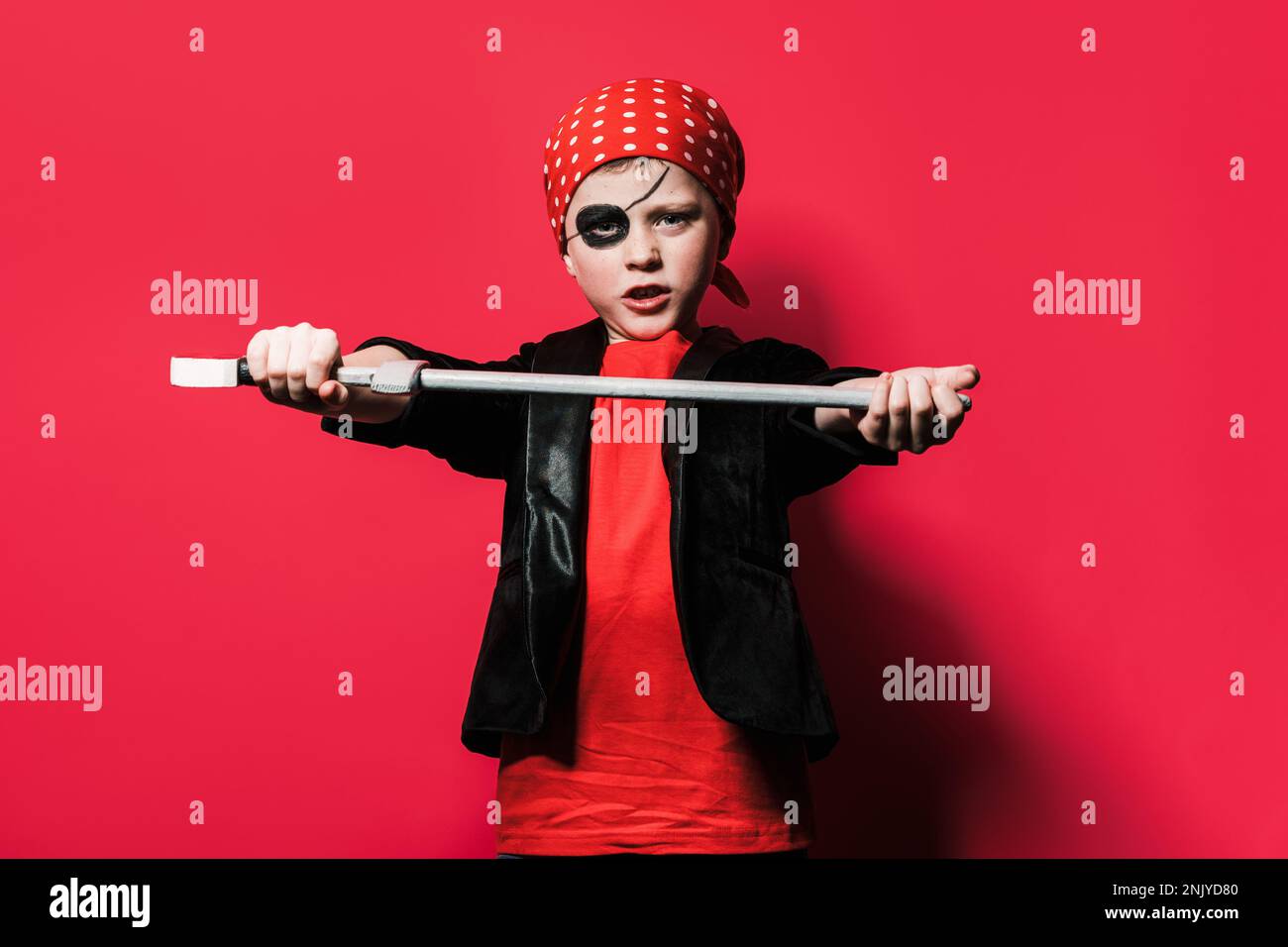 Cute boy in pirate outfit playing with sword and looking at camera ...