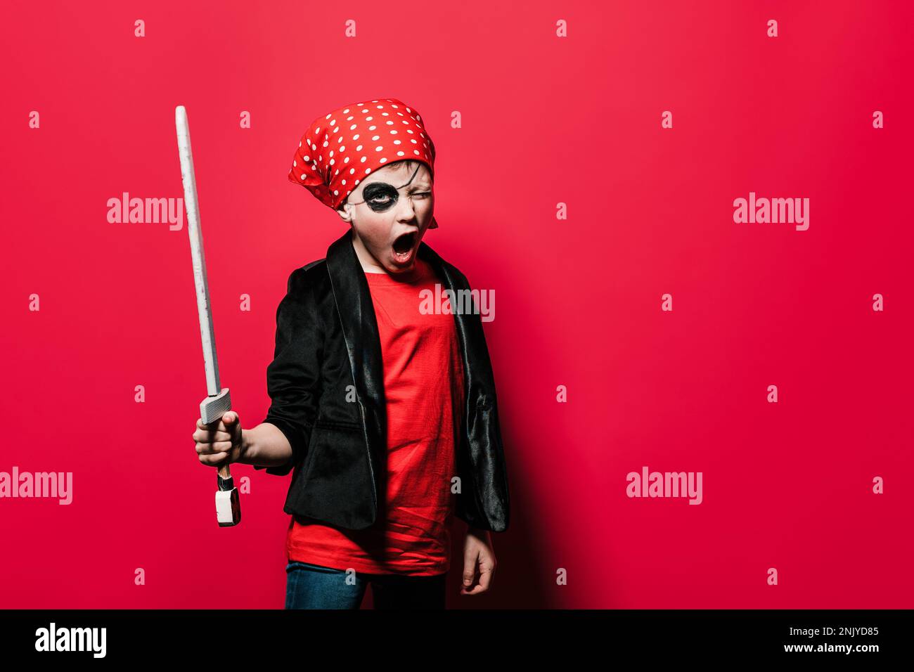 Cute boy in pirate outfit with sword screaming and looking at camera ...