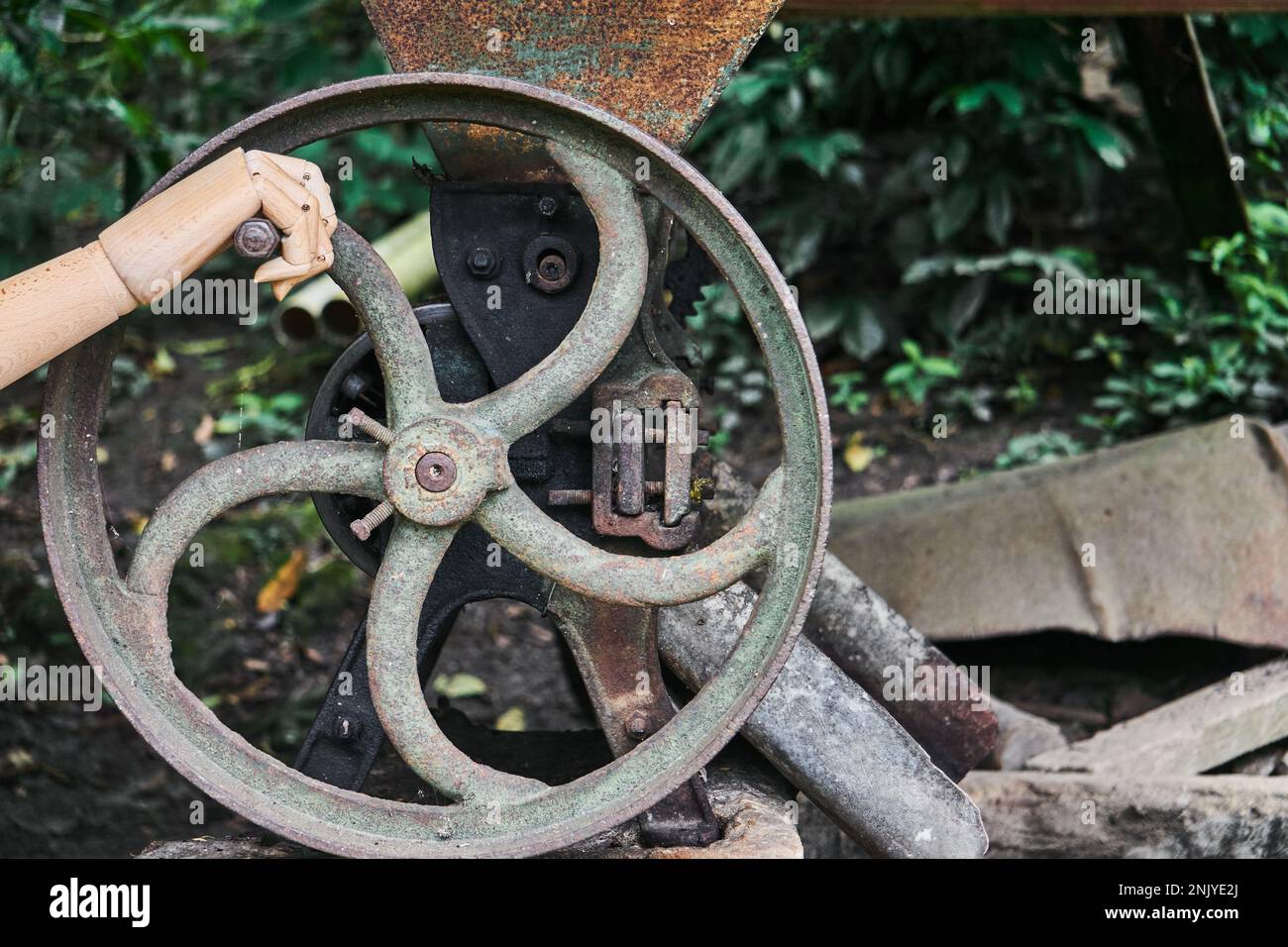 Wooden hand touching metal steering wheel of old rusty machine against ...