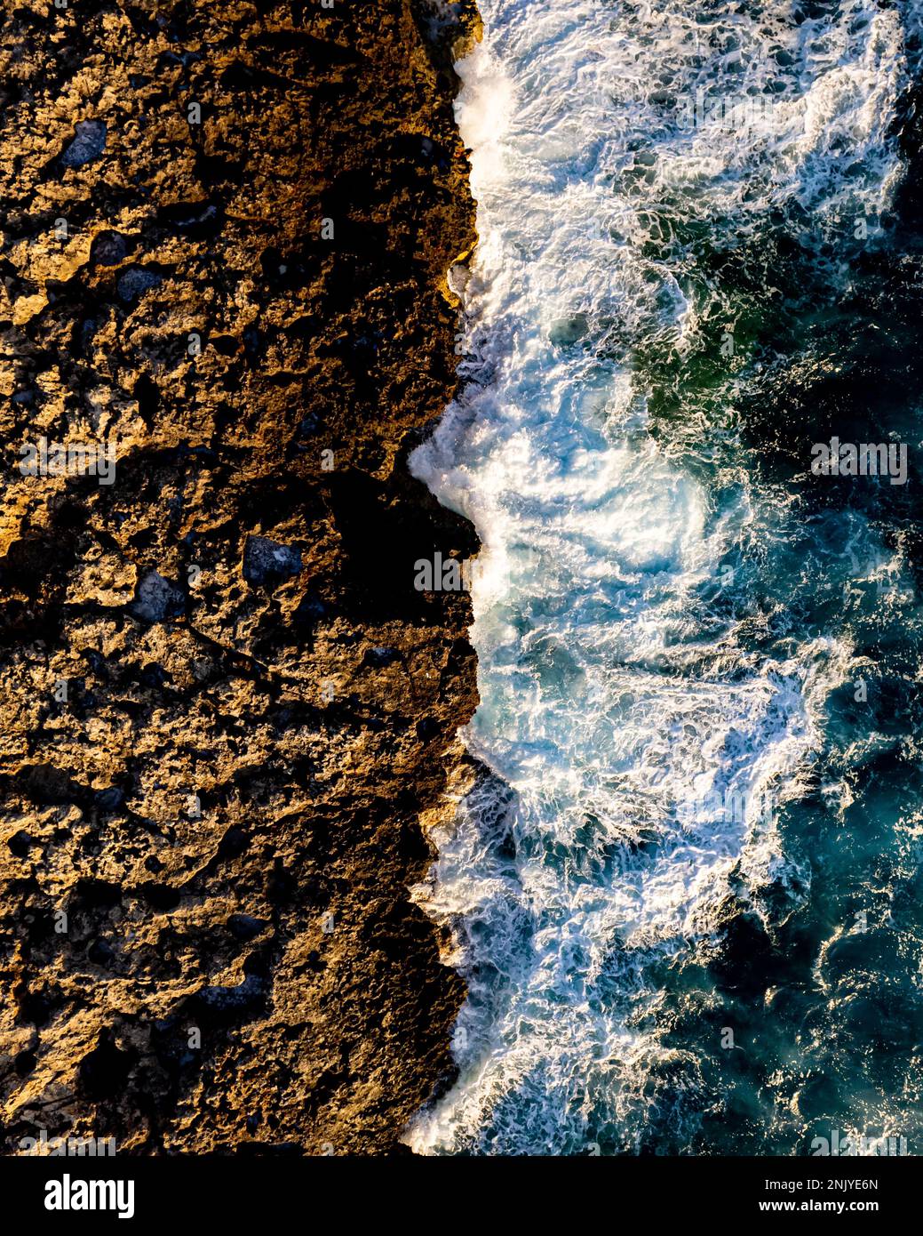 Top aerial view of powerful stormy sea waves splashing on rocky cliff ...