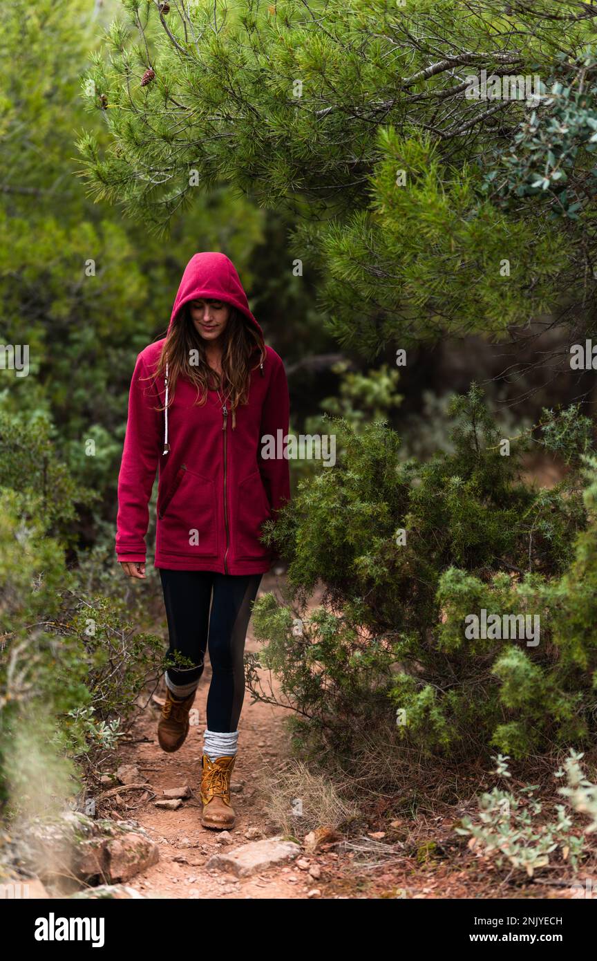 Full body of female hiker in warm clothes and boots walking along ...