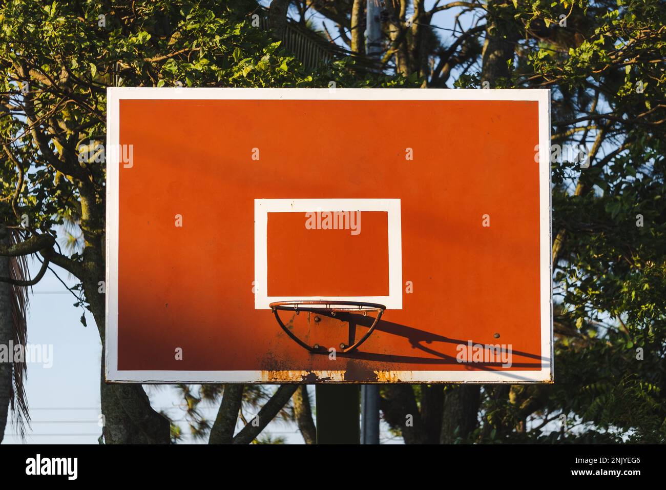 Basketball ring hanging on rusted orange and white painted backboard ...