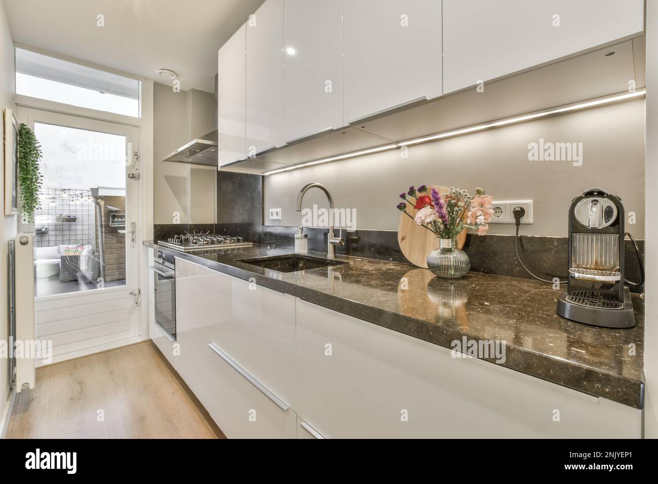 White cupboards and counters with marble countertop located near door ...