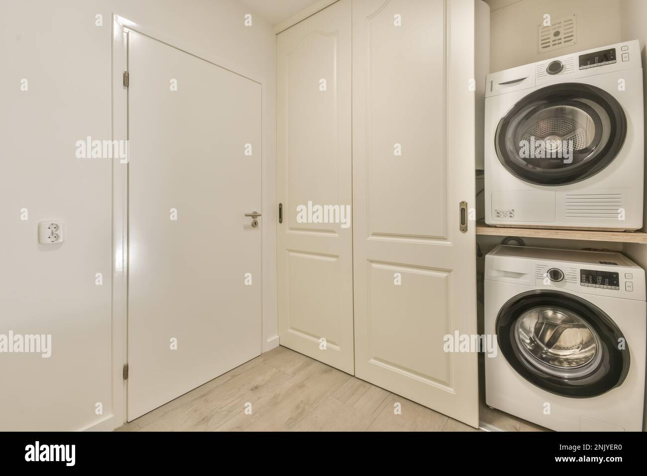 Washing machine and clothes dryer located near wardrobe and closed door ...